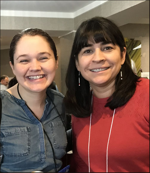 Eileen and Lacey are in the hallway, smiling at the camera.